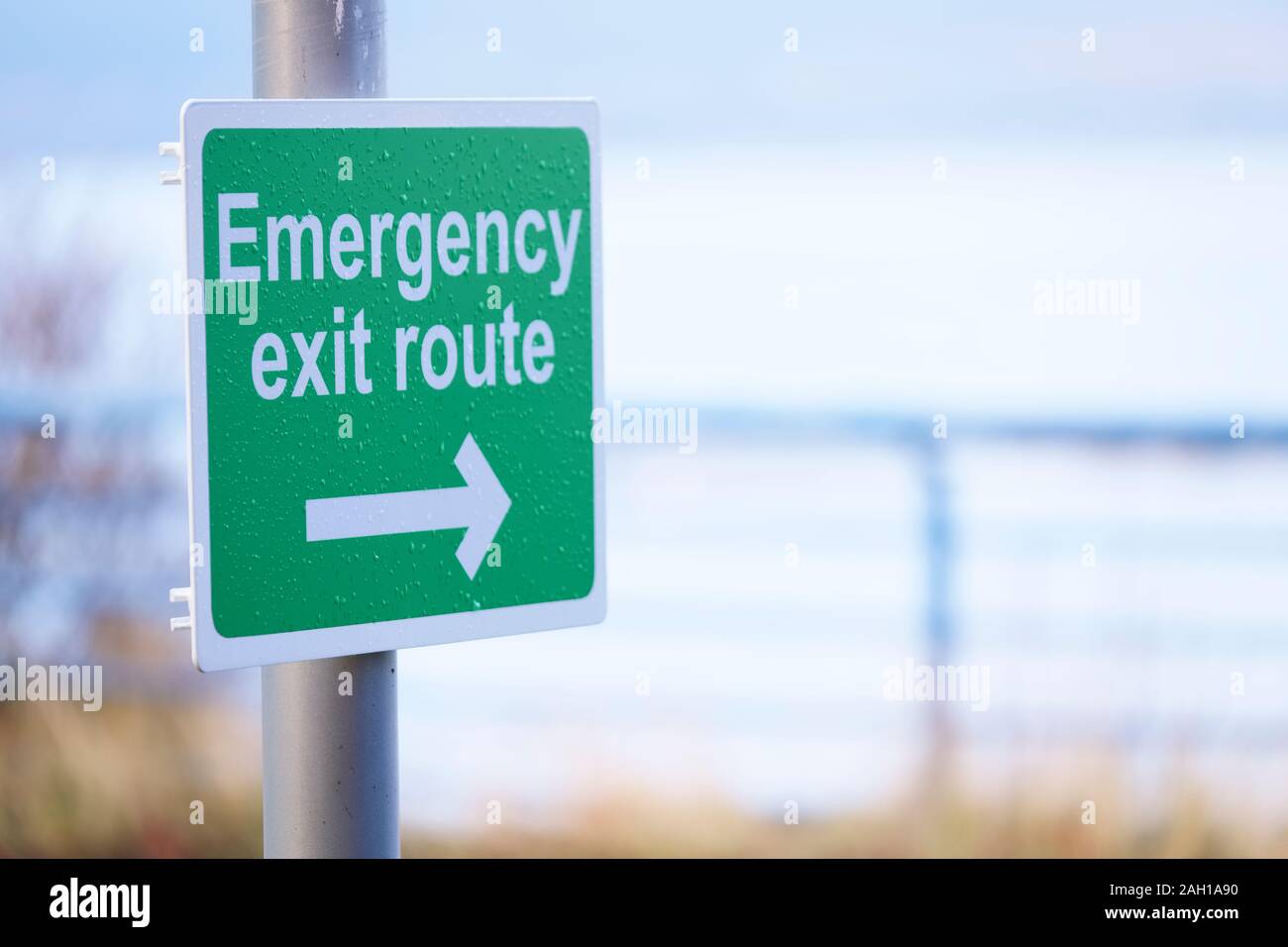 Emergency escape route green sign with direction arrow Stock Photo - Alamy