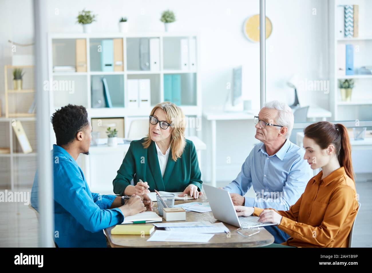 Mature female leader talking to her employees and giving them some ...