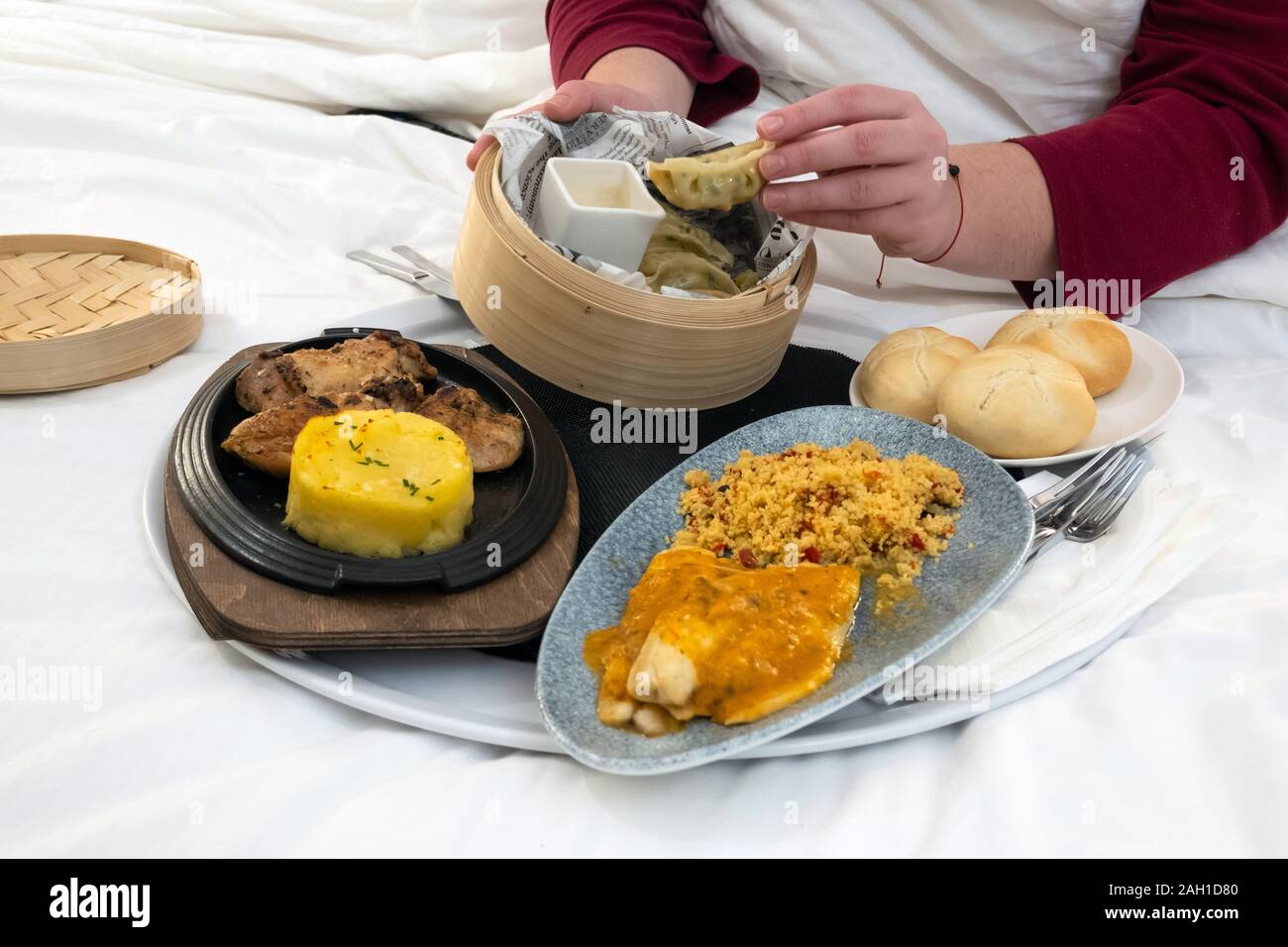 Room service food on the bed in a hotel room. Woman enjoying luxurious ...