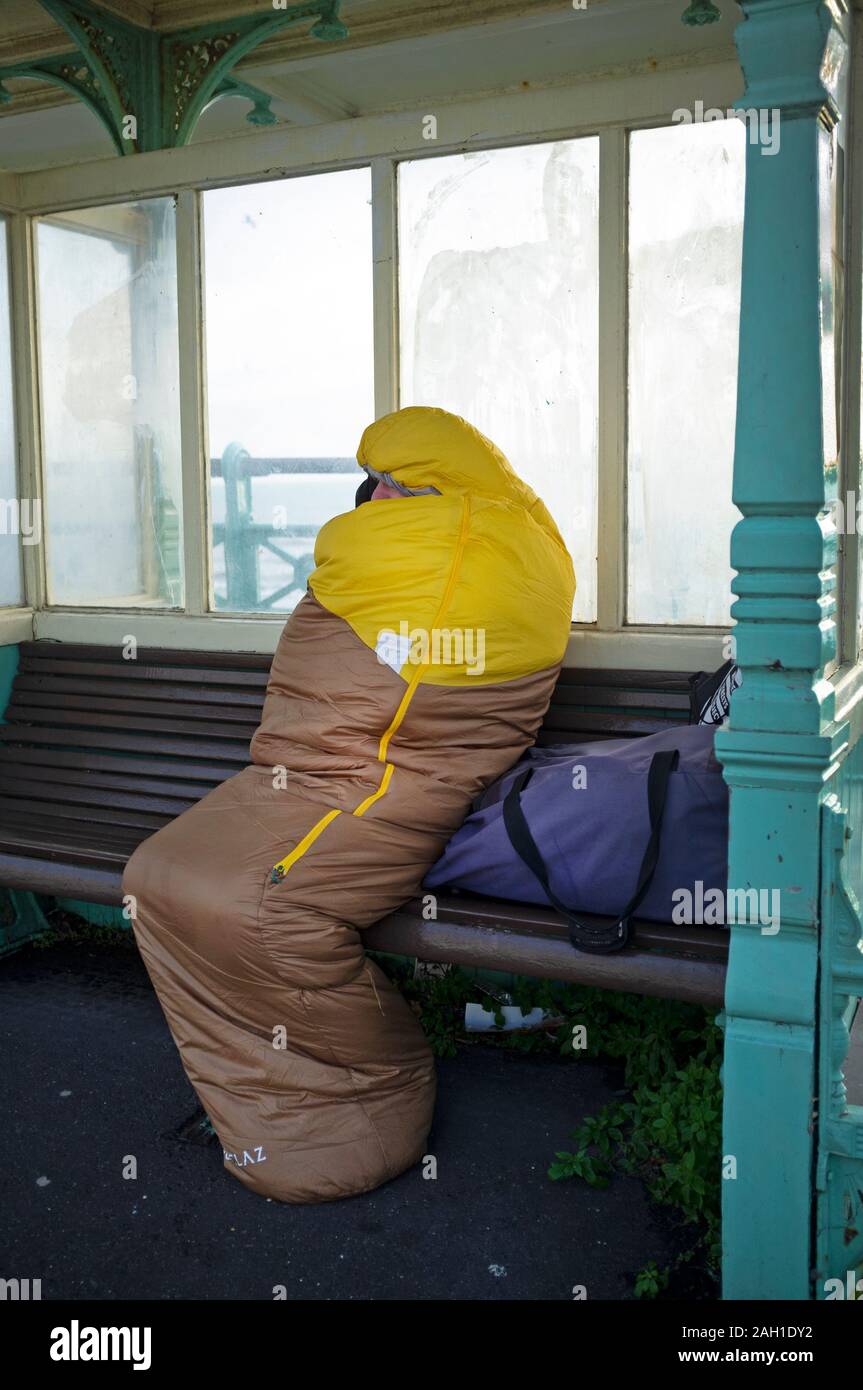 A homeless man tries to keep warm in a Brighton seafront shelter Stock ...