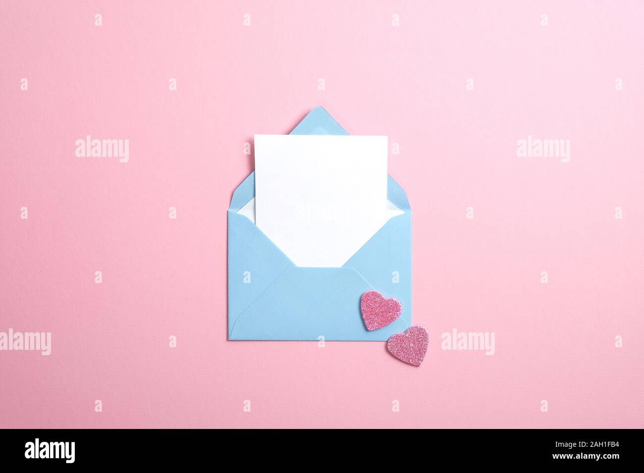 Blue envelope with blank white paper note inside and Valentines hearts ...