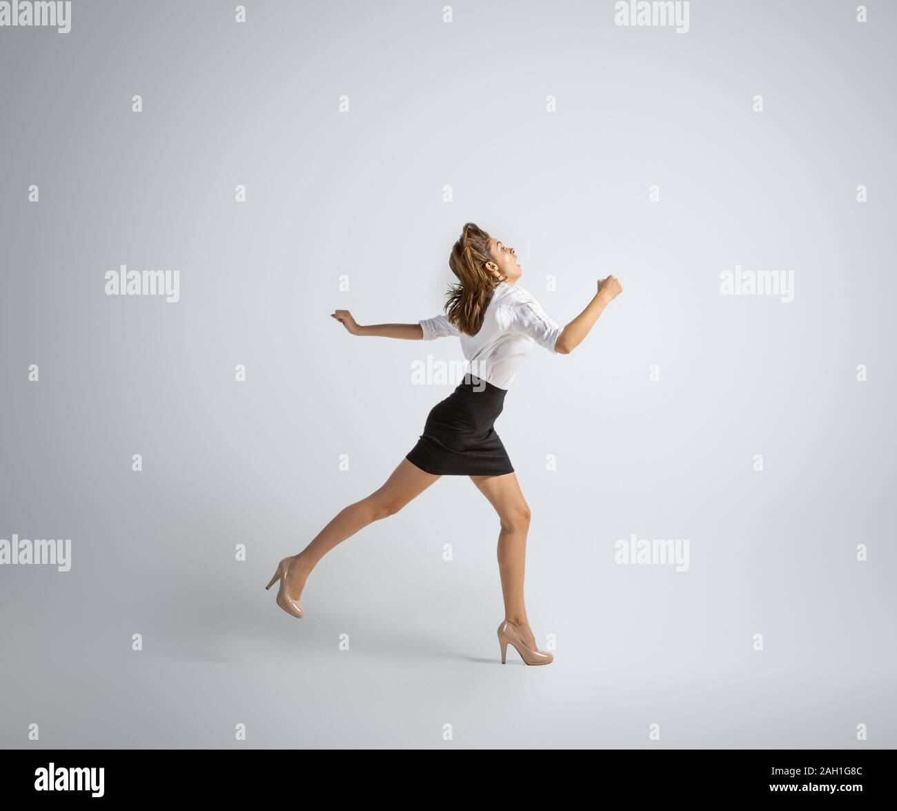 Hurrying up to new goals. Woman in office clothes running on grey ...
