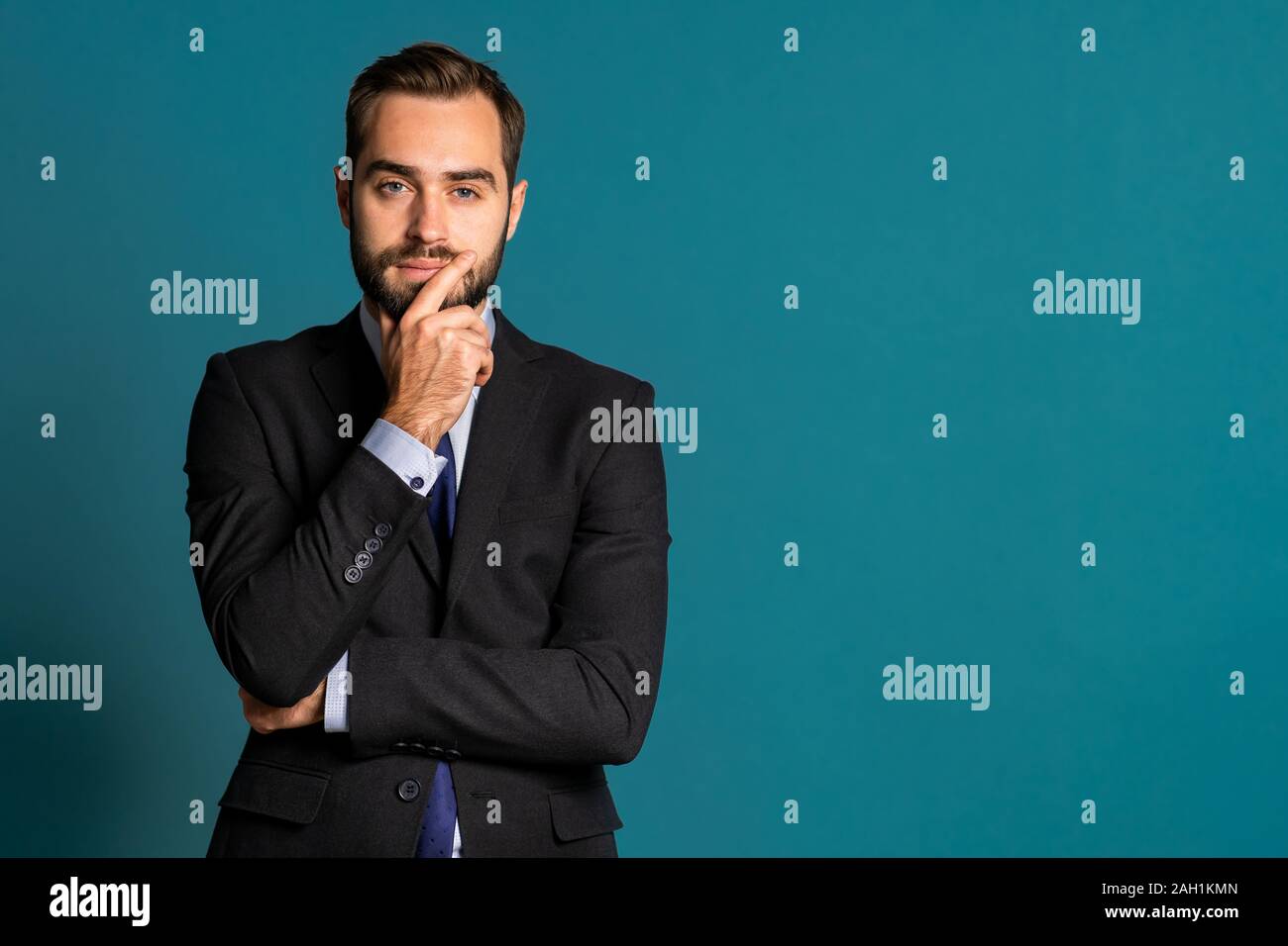 Serious thinking businessman looking around on blue background ...