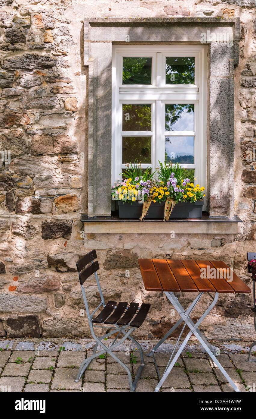 Chair and table of shaded street cafe by a decorated window on Romantic ...
