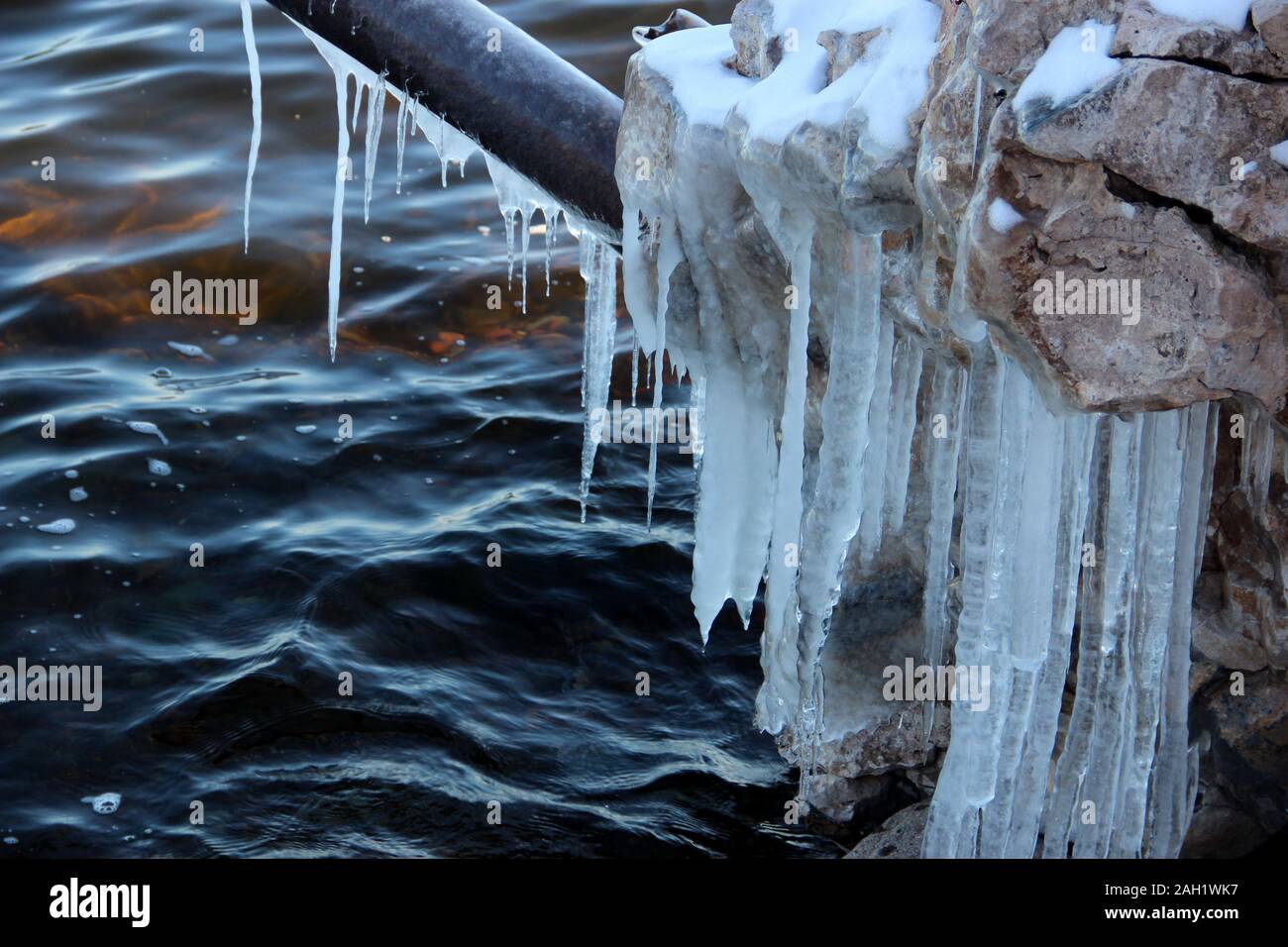 Icicles hanging from a rock & pipe Stock Photo - Alamy