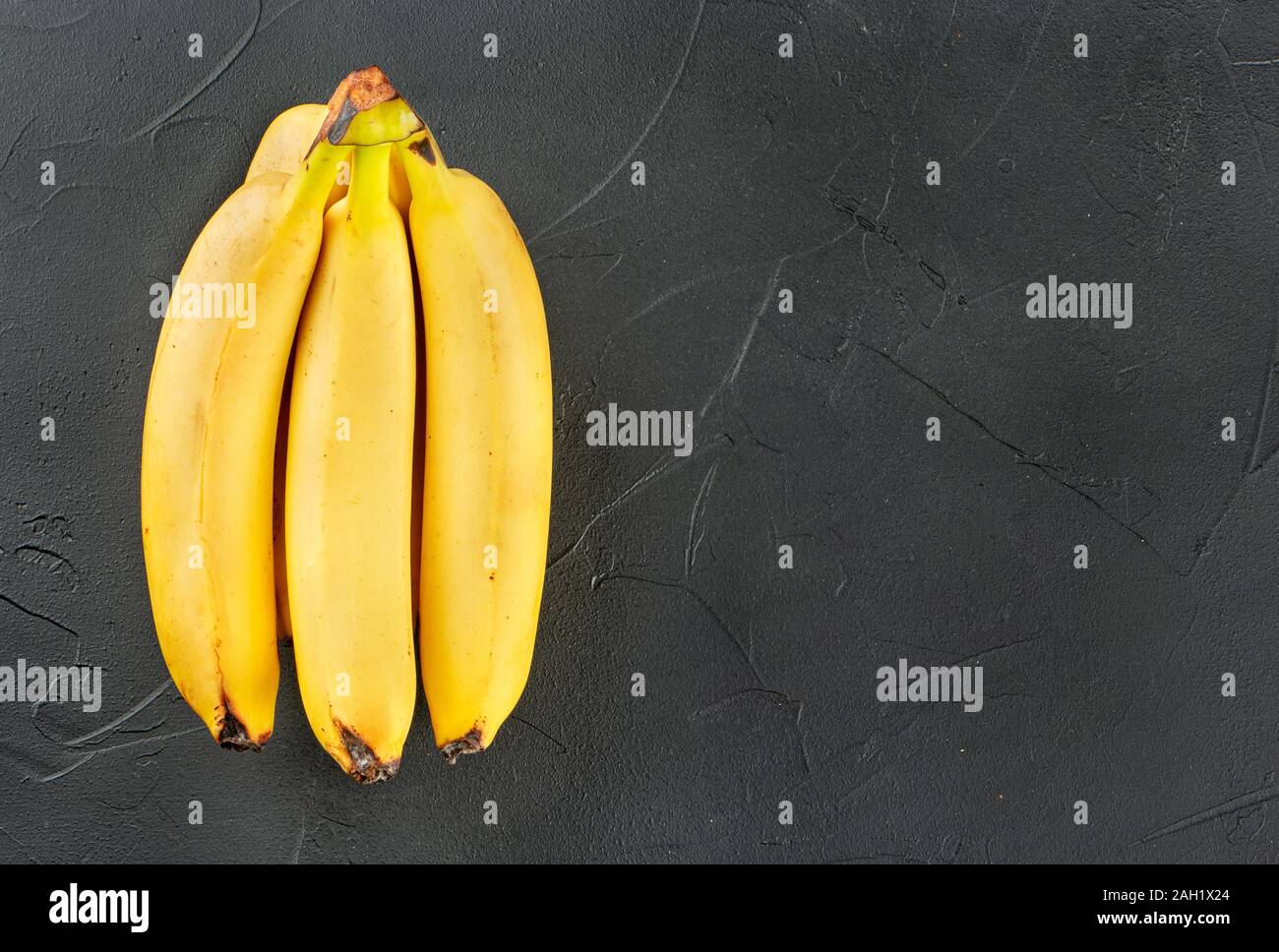 Branch of ripe bananas on an empty dark concrete background Stock Photo ...