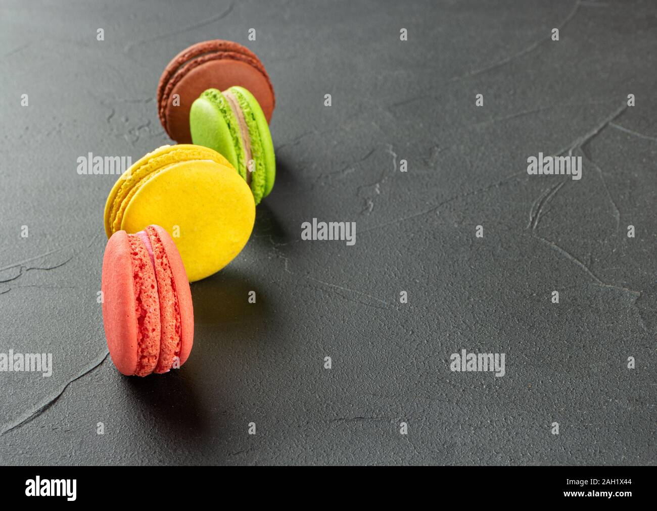 Sweet four colored macaroons on dark background Stock Photo - Alamy