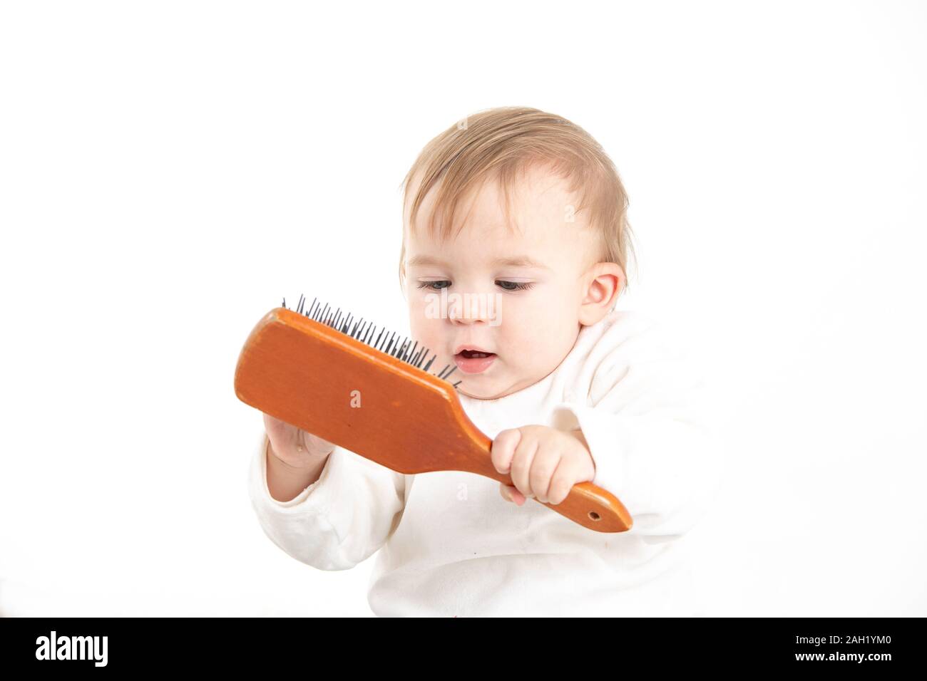 Stock studio photo with a white background of a baby with a comb in his ...