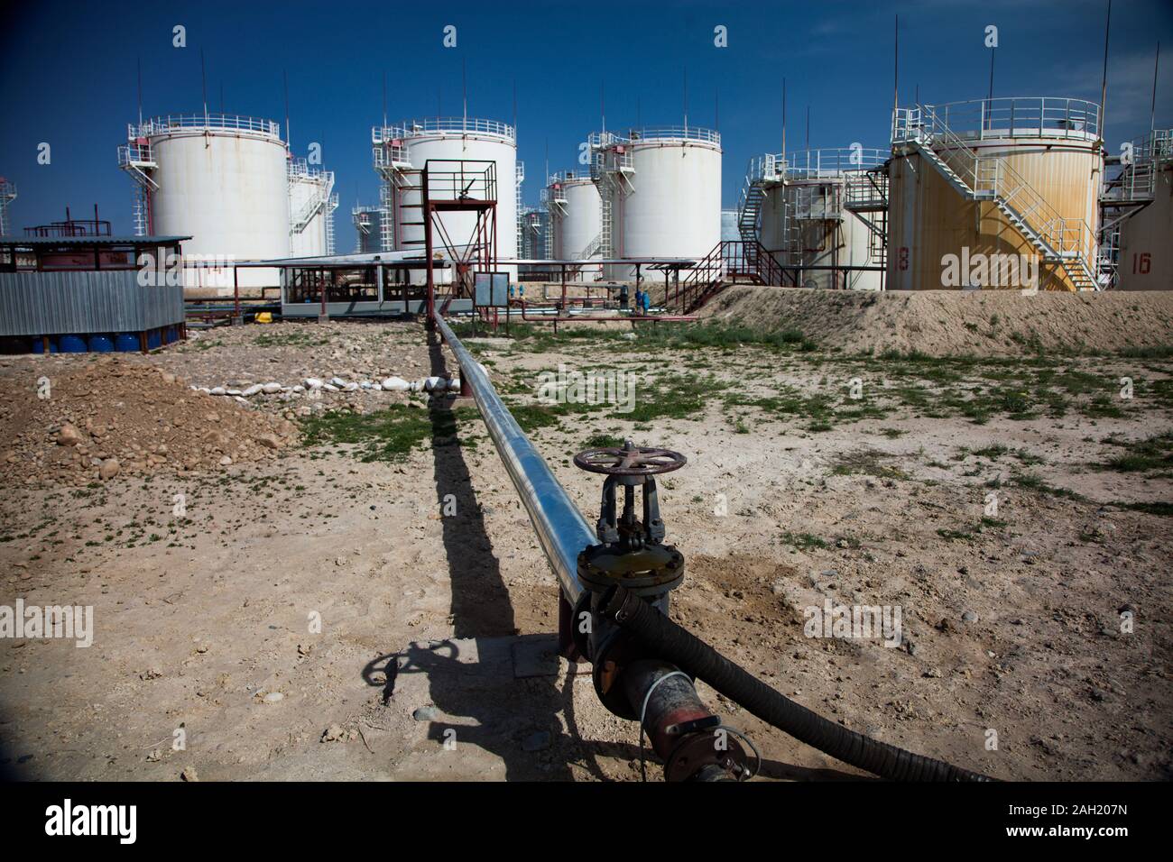 White and yellow oil tanks on bright sun on a deep blue sky with light ...