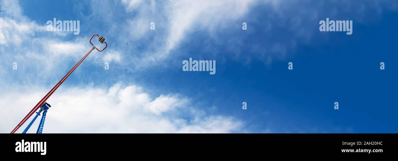 People ride on the extreme carousel on blue sky background, panoramic ...