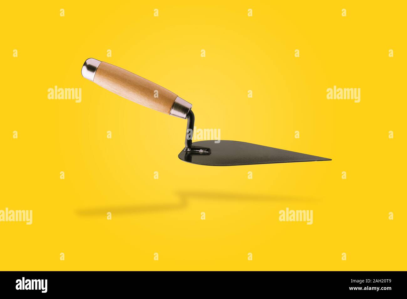 Triangle trowel over yellow background, new construction tool concept ...