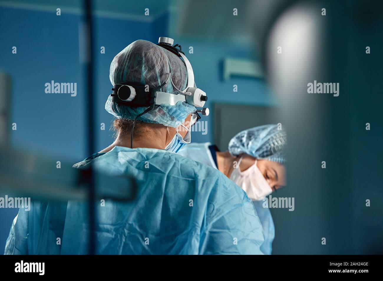 Two surgeons in protective uniform during the operation, on background ...