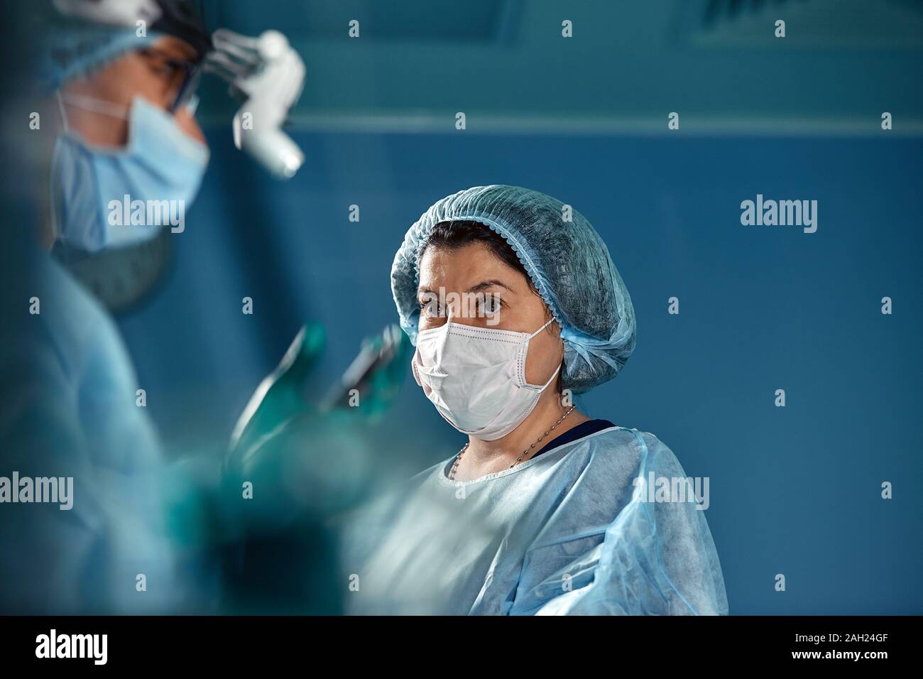 Two surgeons in protective uniform during the operation, on background ...
