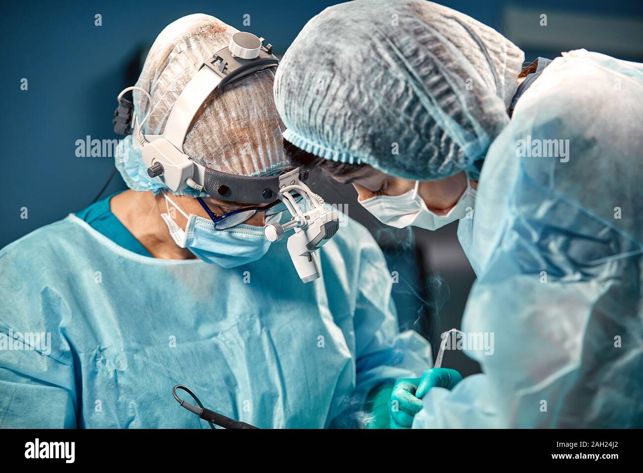 Two surgeons in protective uniform during the operation, on background ...