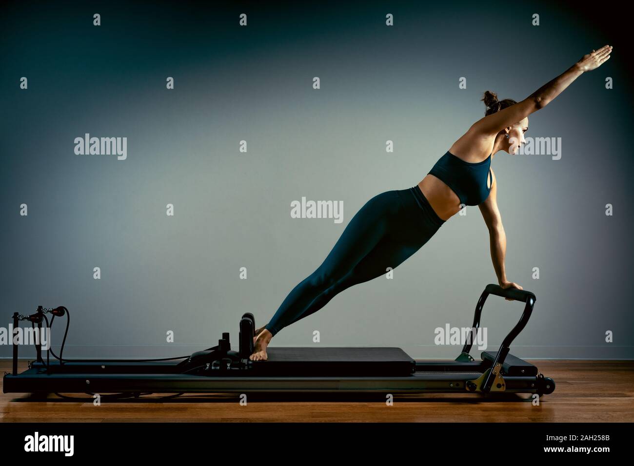 Young girl doing pilates exercises with a reformer bed. Beautiful slim ...