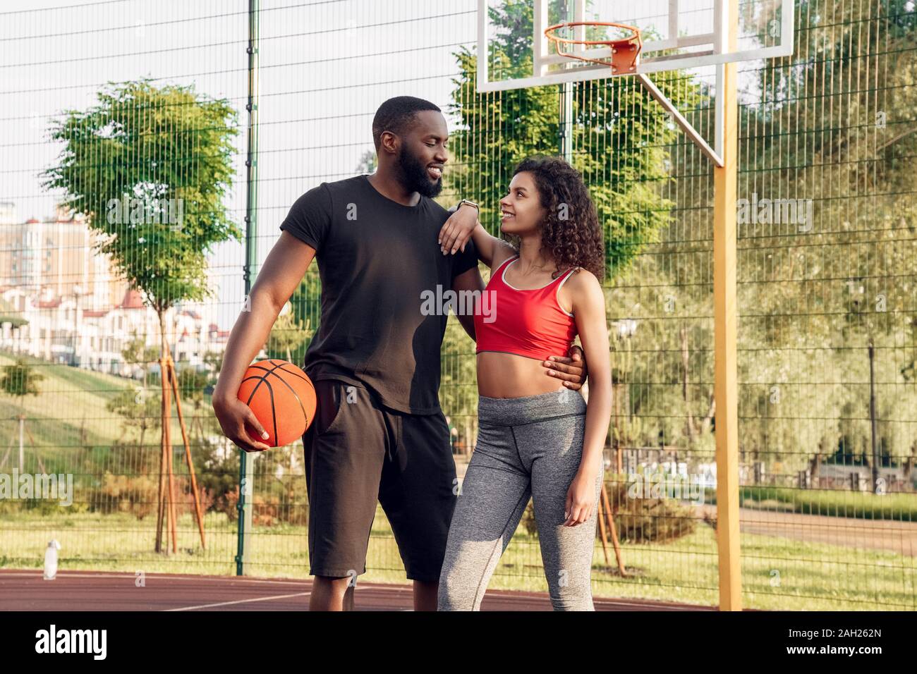 Perfect Team. African couple standing with ball hugging on basketball ...