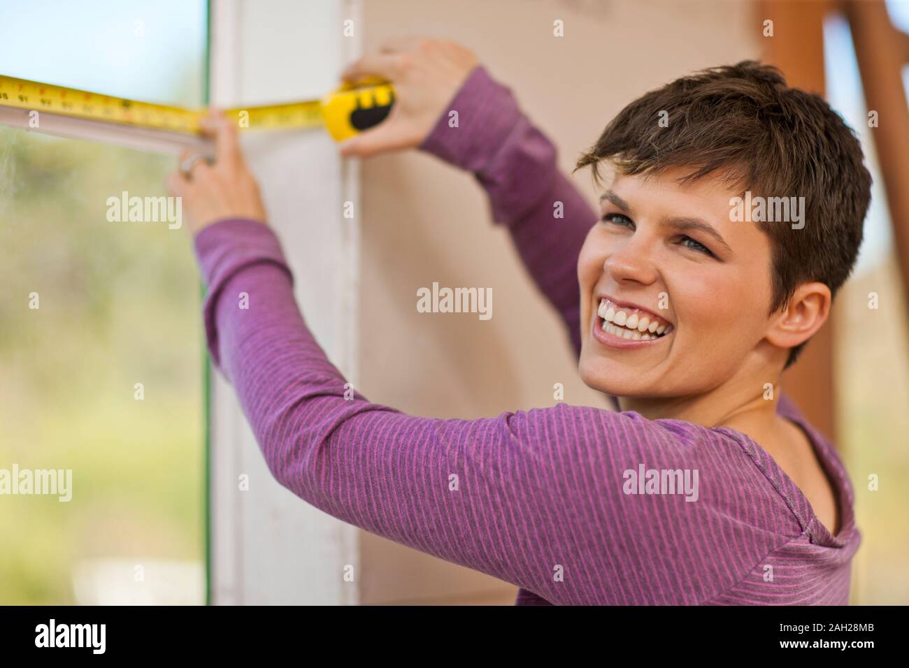 Mid adult woman smiling while using a tape measure Stock Photo - Alamy