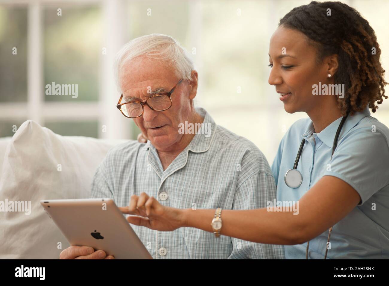 Female nurse showing a senior man how to use an iPad Stock Photo - Alamy