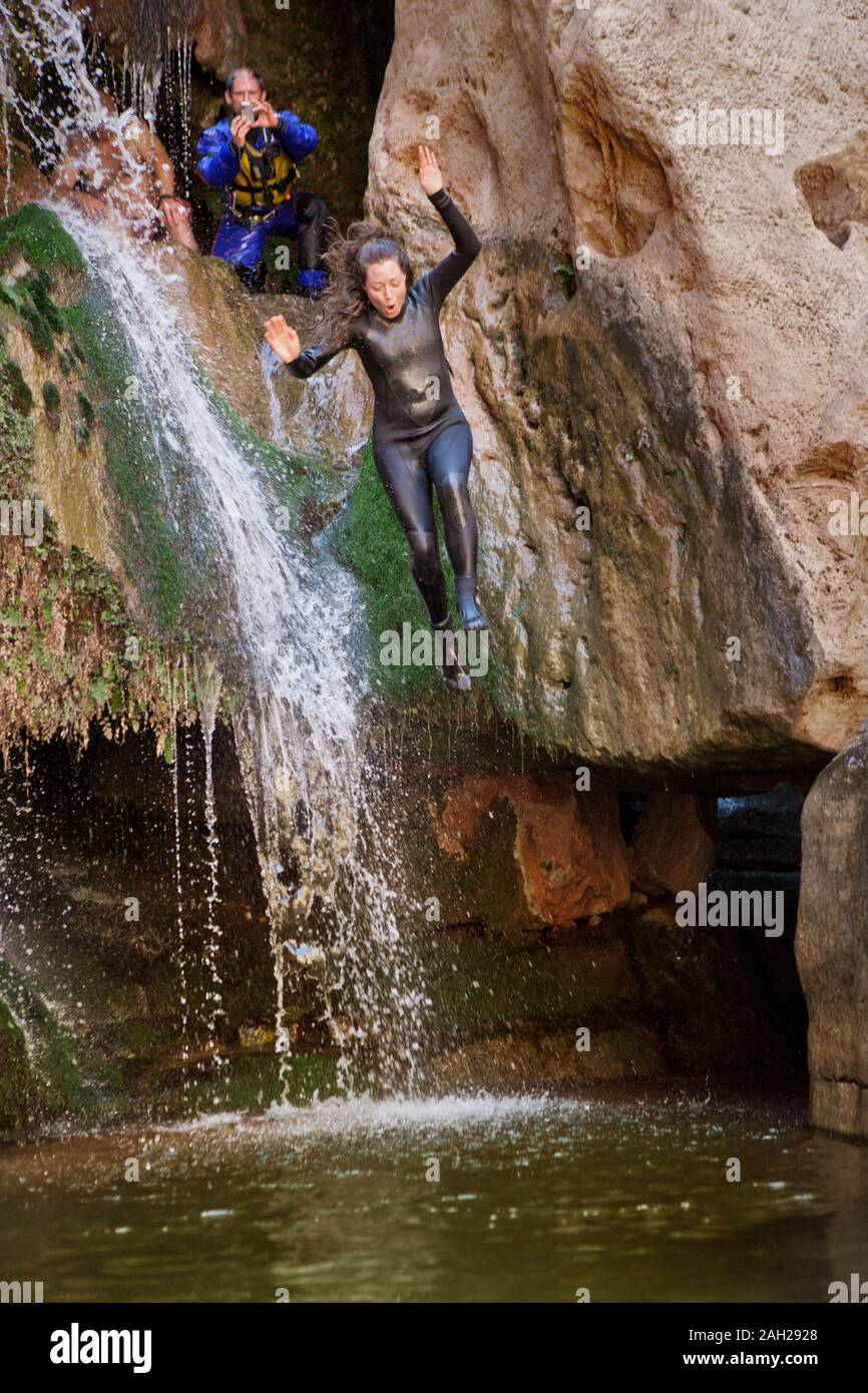 Young woman jumping into a pool below a waterfall Stock Photo - Alamy