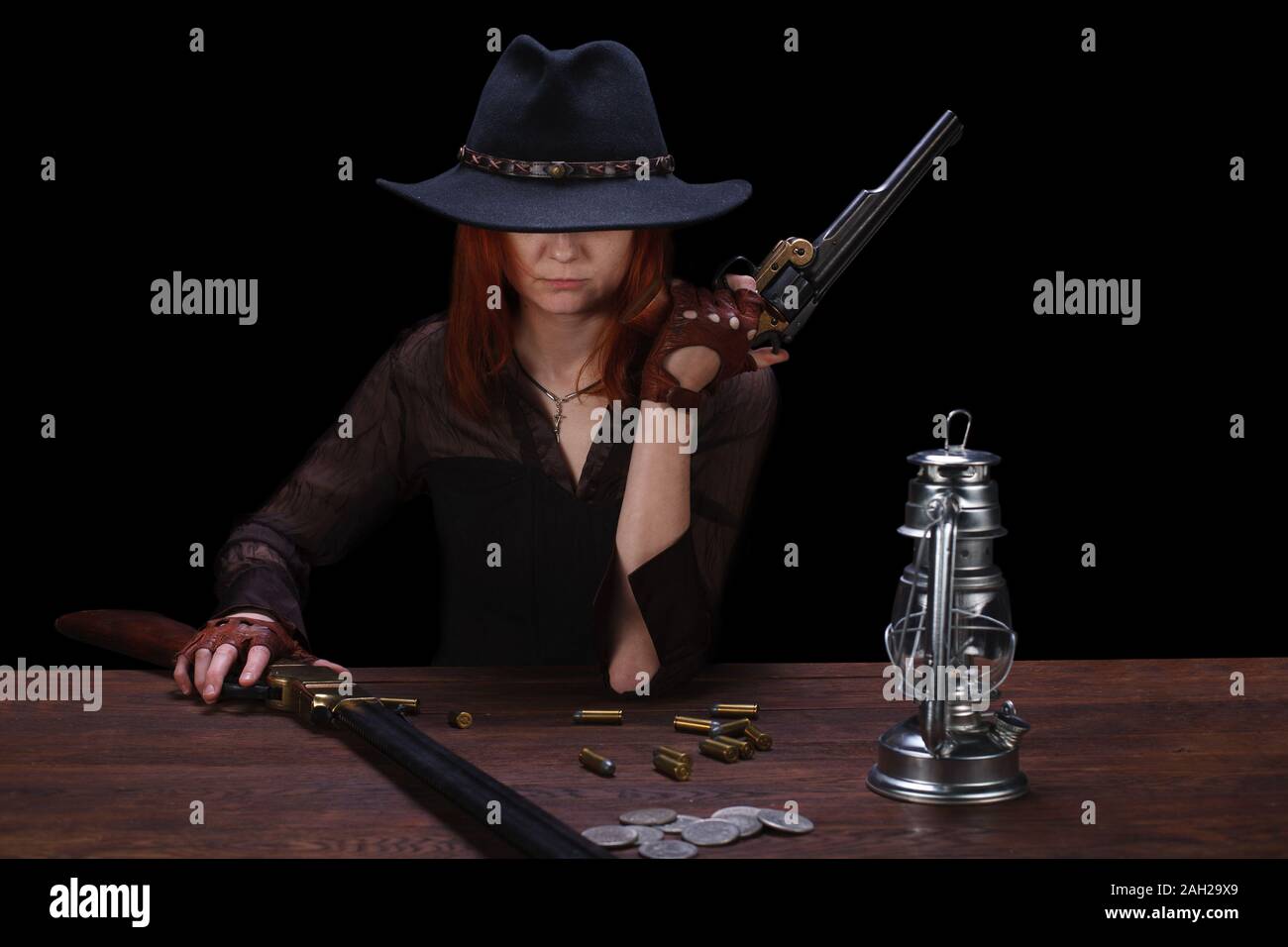 wild west girl with revolver gun sitting at the table with ammunition ...