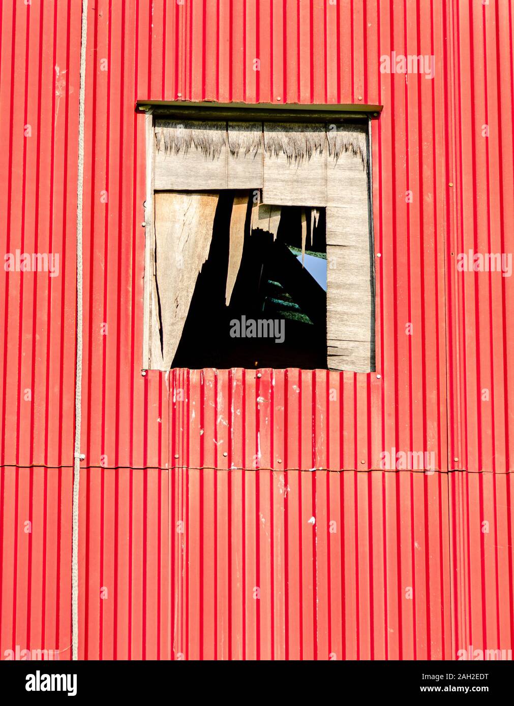 A broken window in a barn whose outside wall is made of corrugated ...