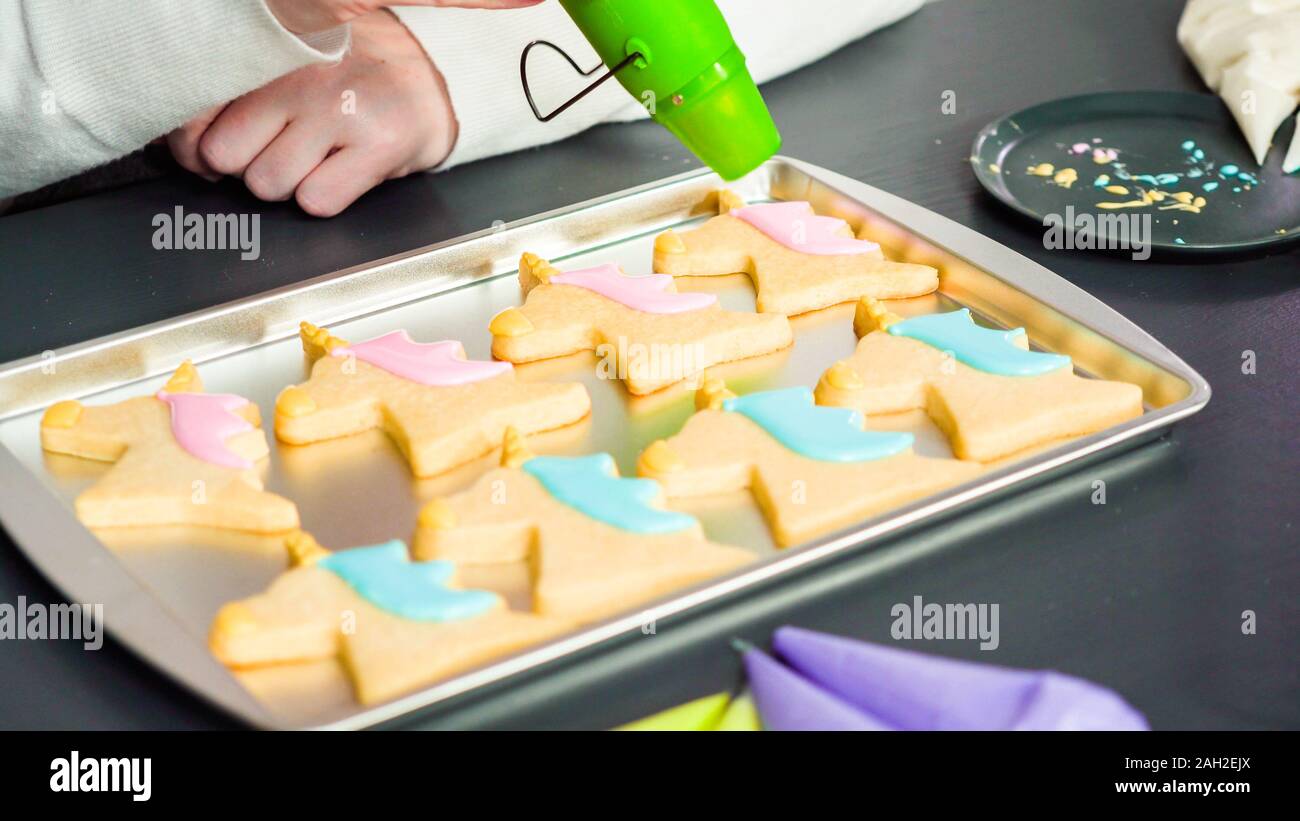 Decorating unicorn sugar cookies with multi-color royal icing Stock ...
