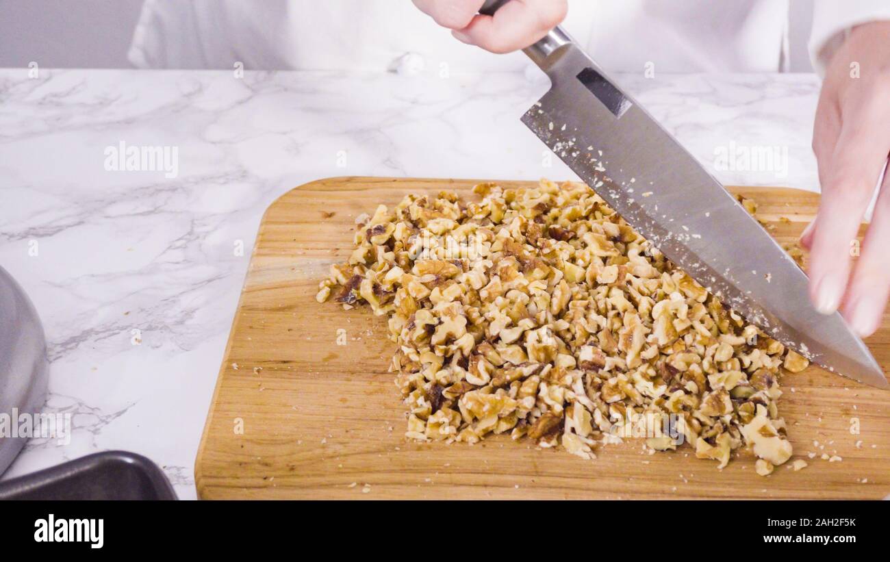 Step by step. Chopping walnuts with kitchen knife on a wood cutting ...