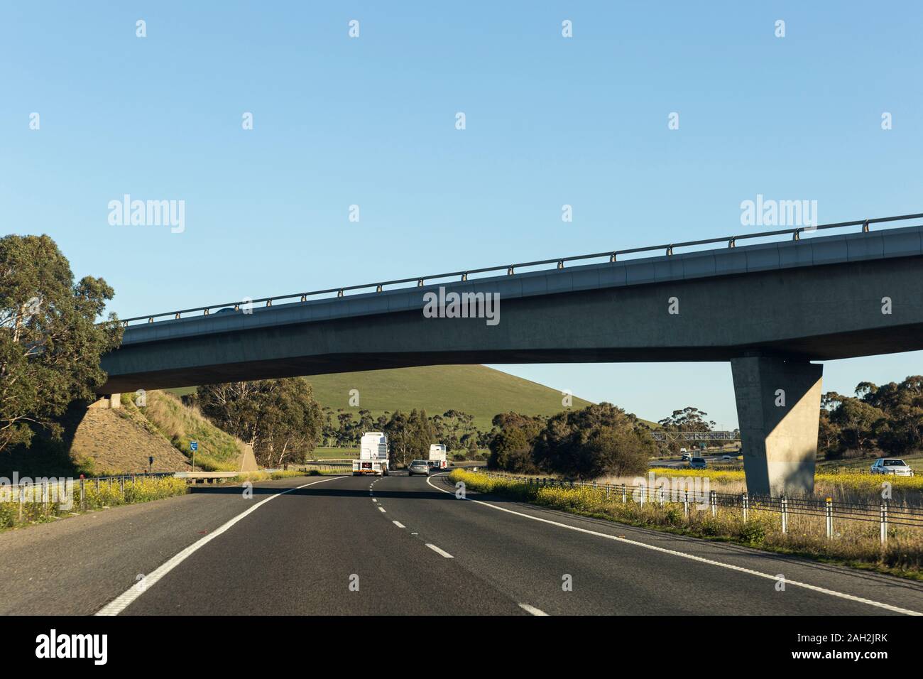 Modern bridge crossing asphalt road with cars on sunny cloudless day in ...