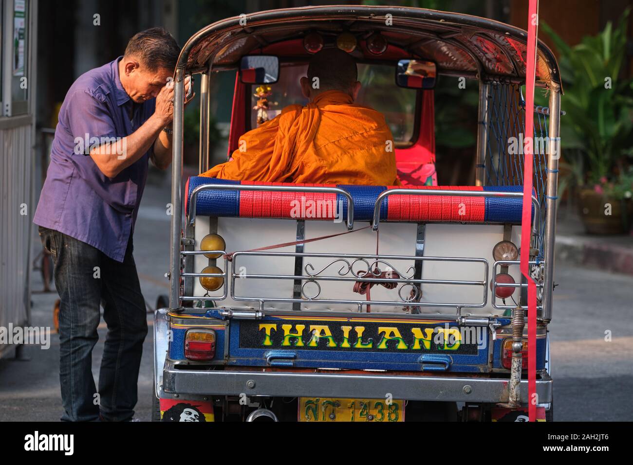 The driver of a tuk-tuk (three-wheeled taxi) 'wais' (respectully greets ...