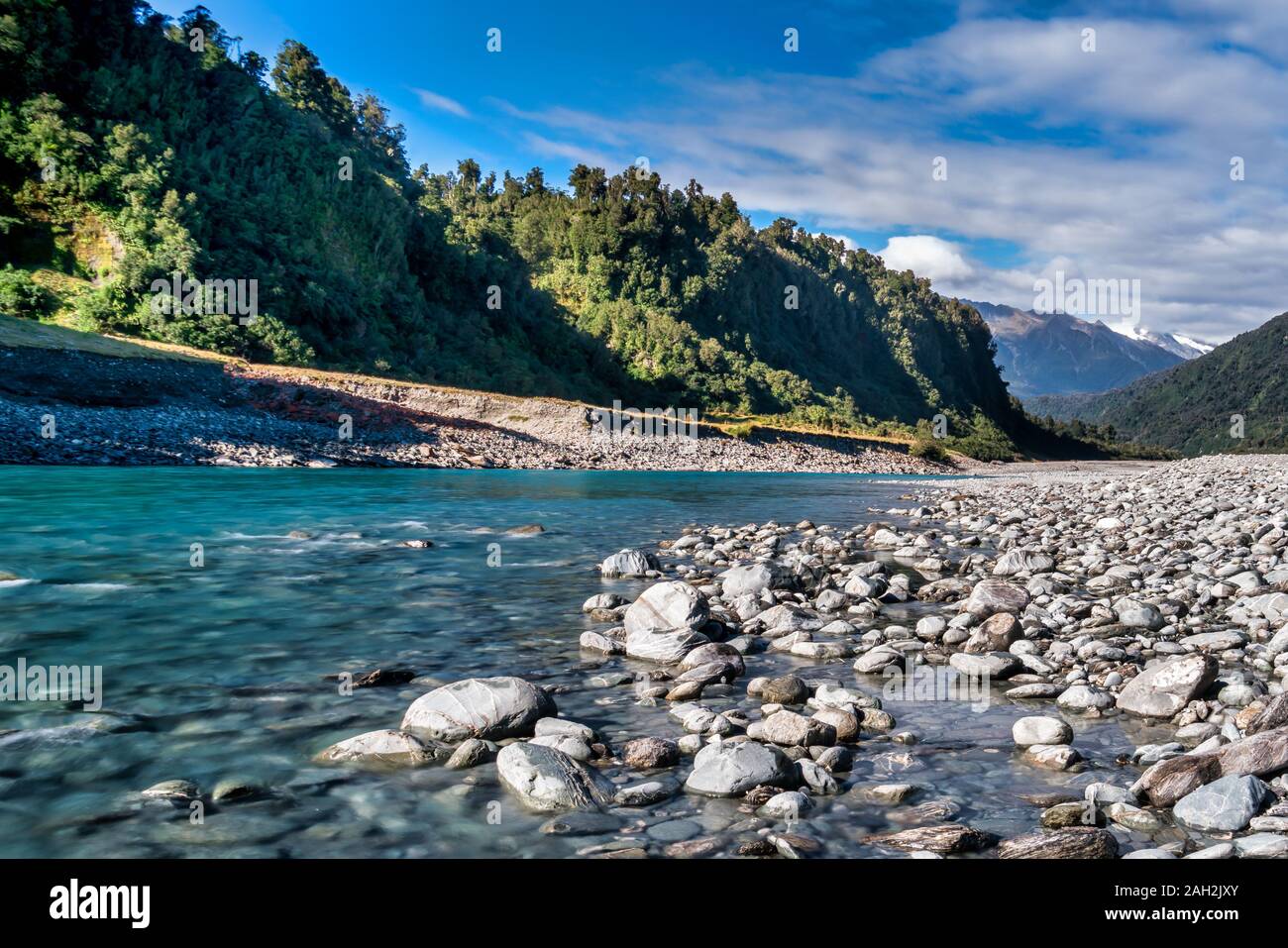 Crystal clear blue water of the swift flowing Whataroa river weaving ...