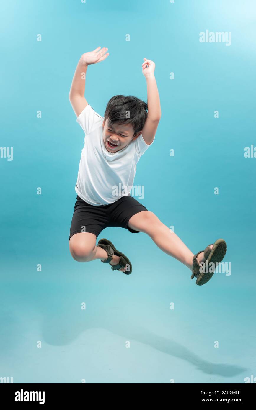 A full length portrait of a handsome child boy jumping in the studio ...