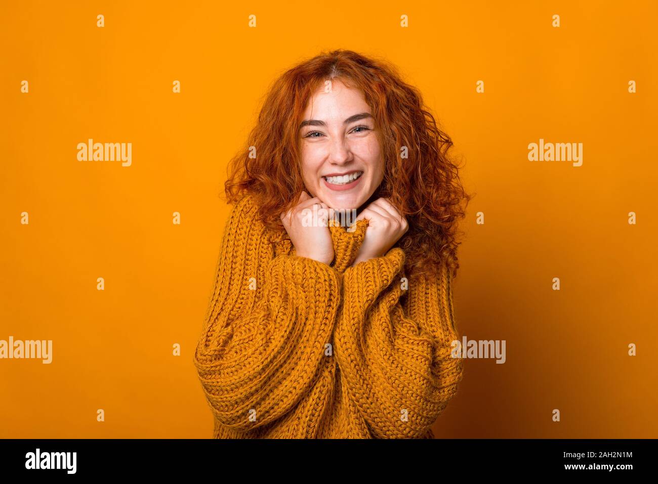 Portrait of ginger girl, standing over orange background, and posing ...