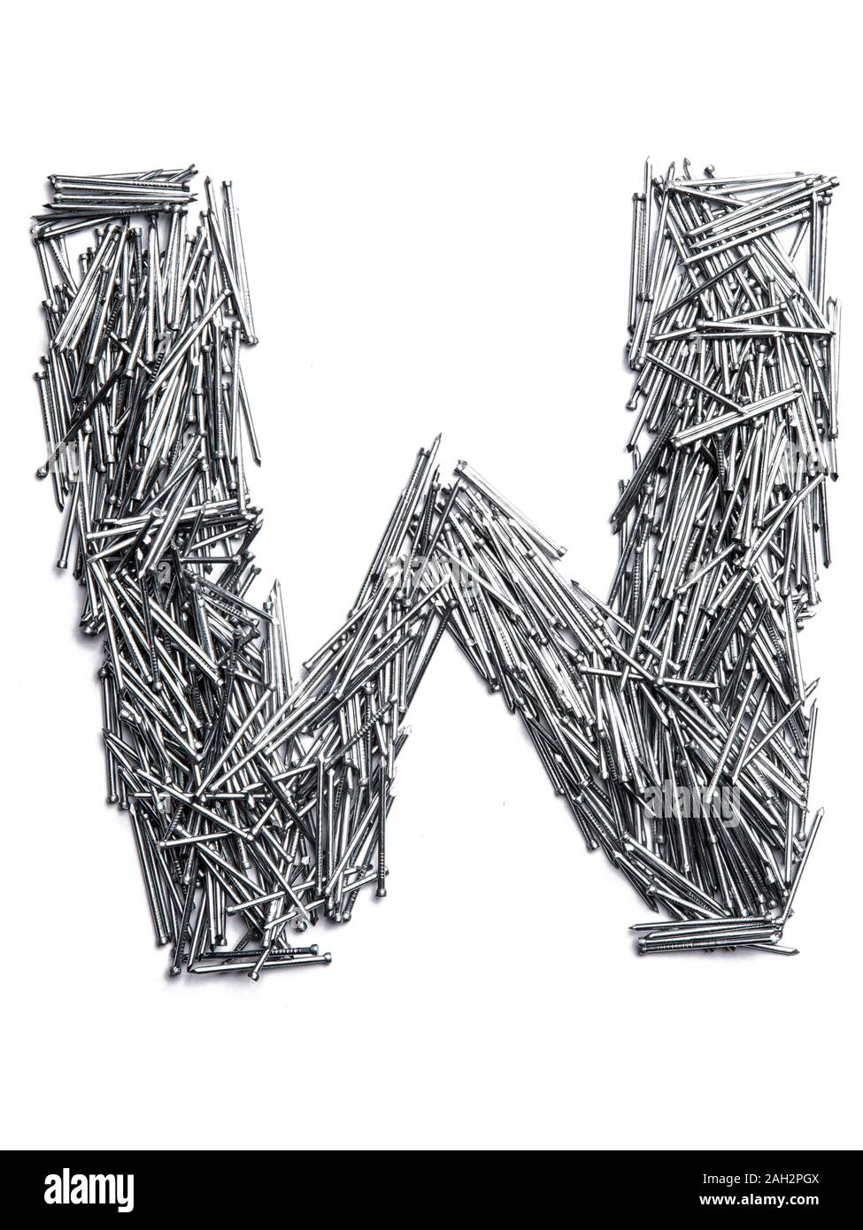 Letter W of the English alphabet from small iron nails on a white ...