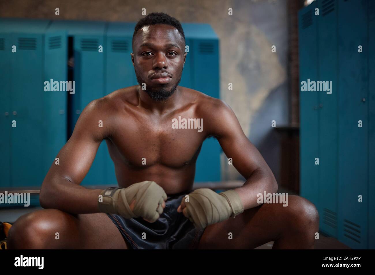 Portrait of African young boxer looking at camera while sitting on ...