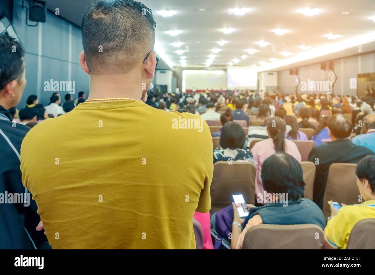 Backside view of spectators standing in a gathering in the back of ...