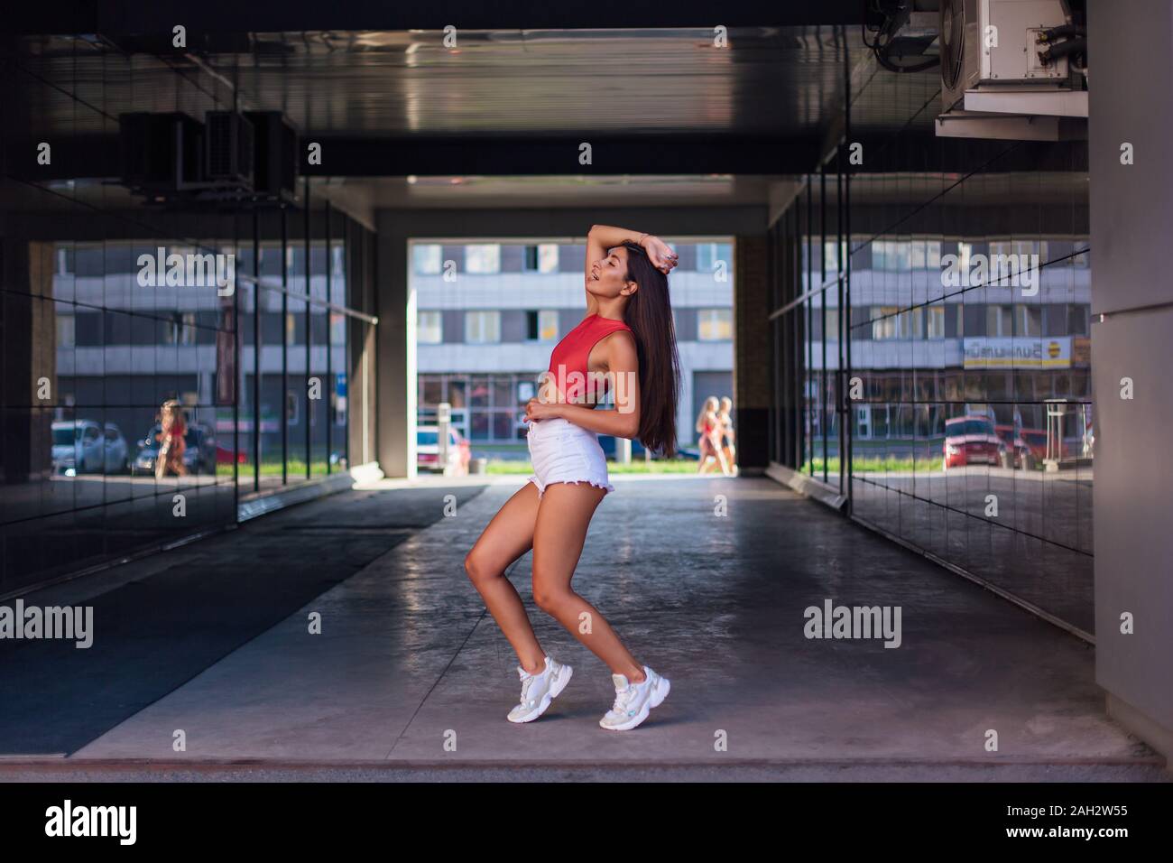 Young brunette woman dancing in arch of building Stock Photo - Alamy