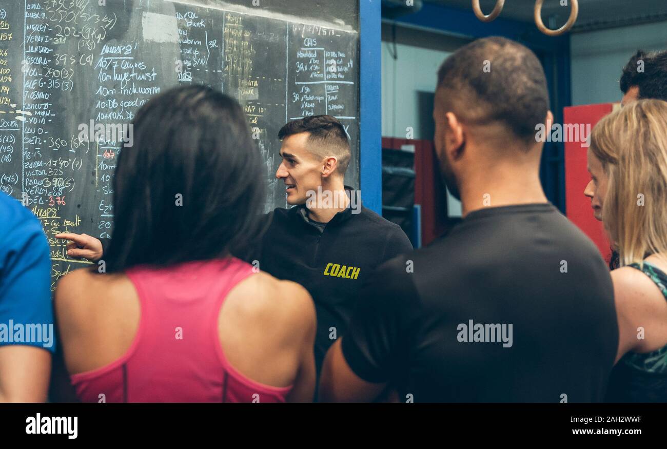 Coach explaining to athletes in the gym Stock Photo - Alamy