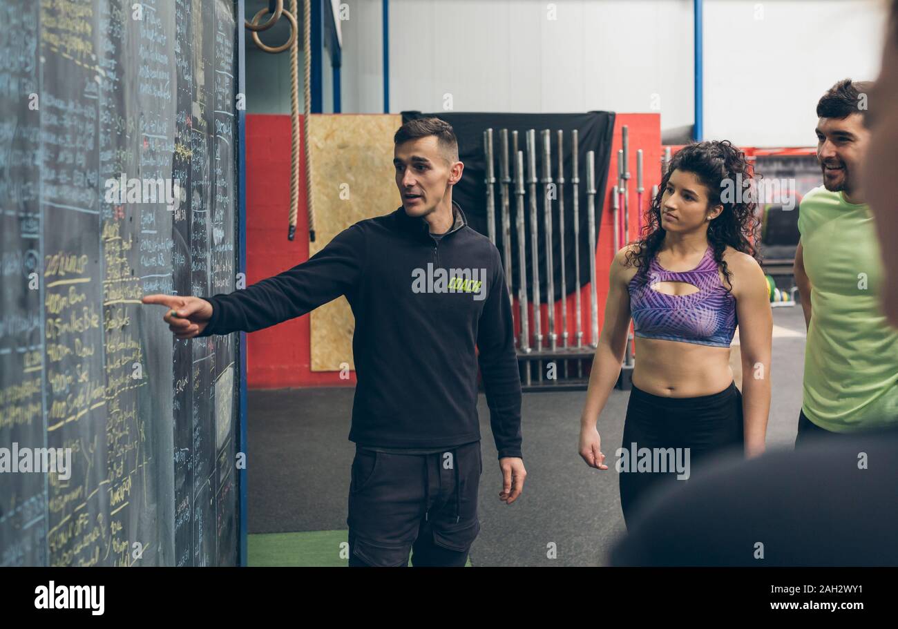 Coach explaining to athletes in the gym Stock Photo - Alamy