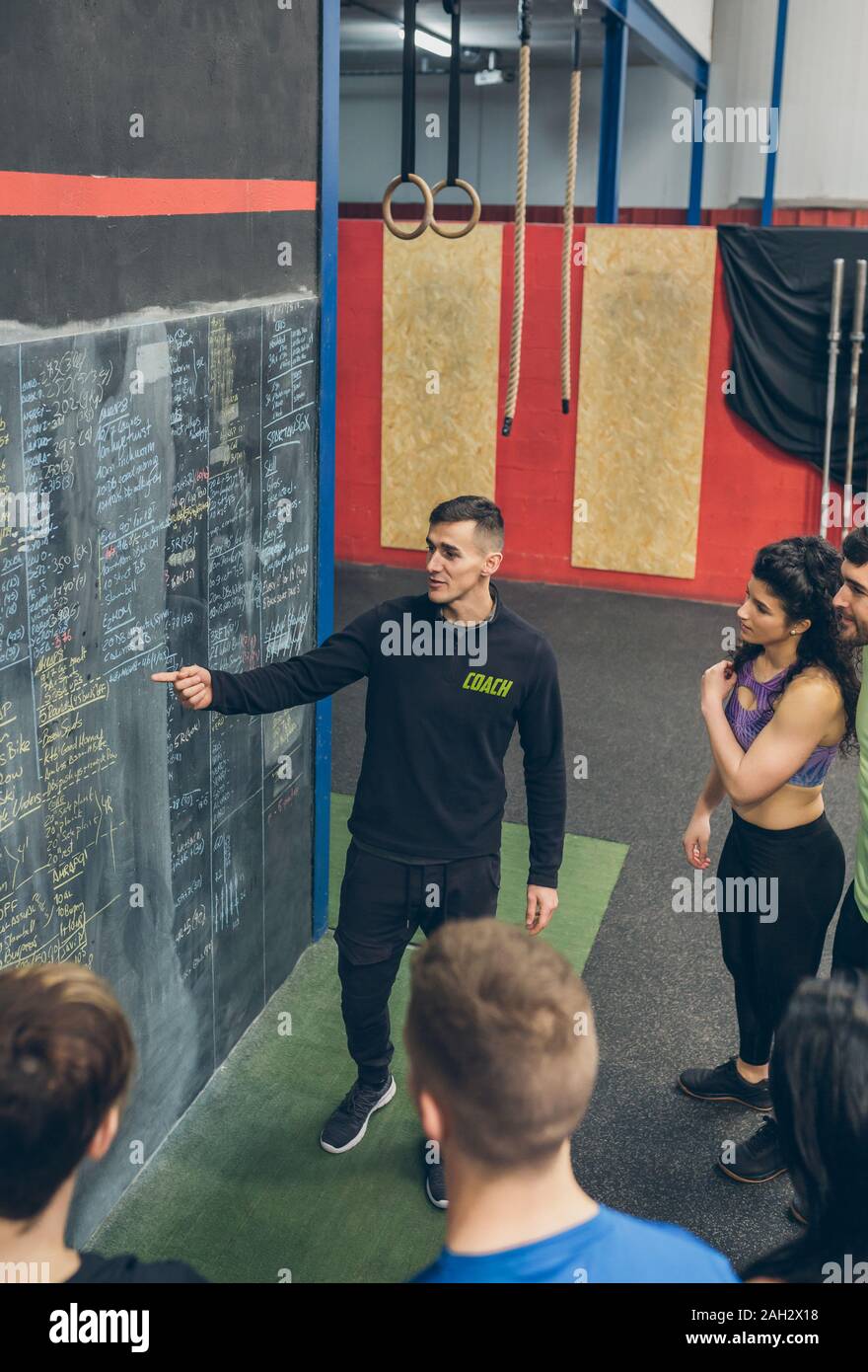 Coach explaining to athletes in the gym Stock Photo - Alamy