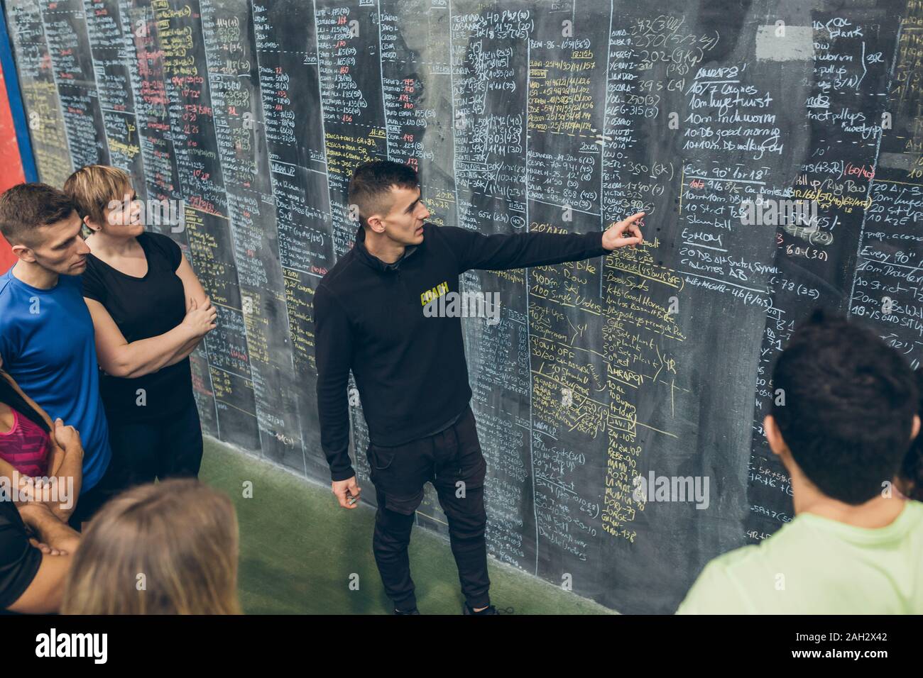 Coach explaining to athletes in the gym Stock Photo - Alamy