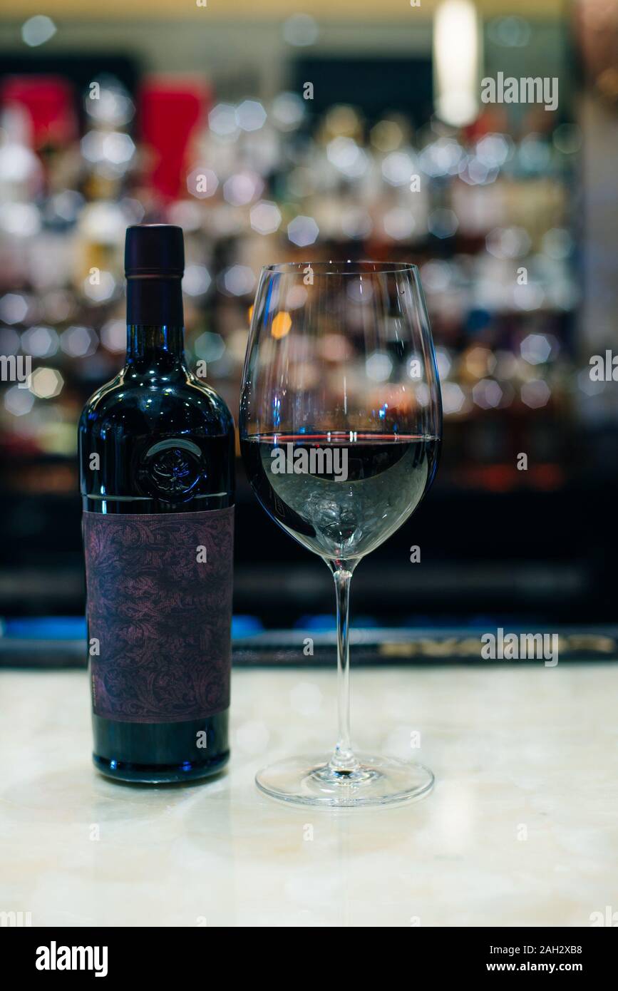 Glass and bottle of red wine on bar counter Stock Photo - Alamy
