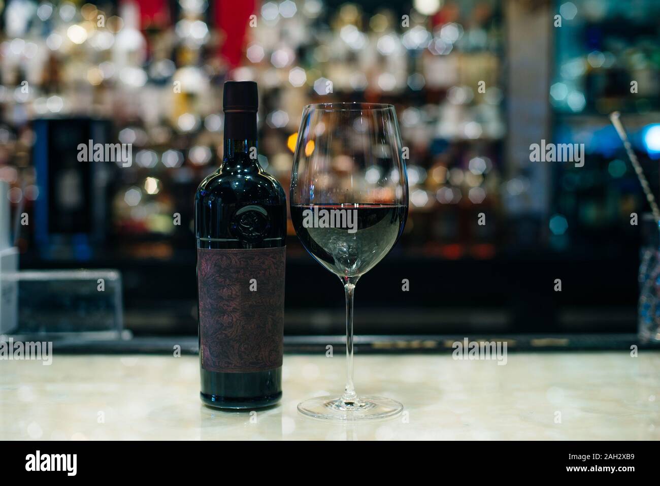 Glass and bottle of red wine on bar counter Stock Photo - Alamy