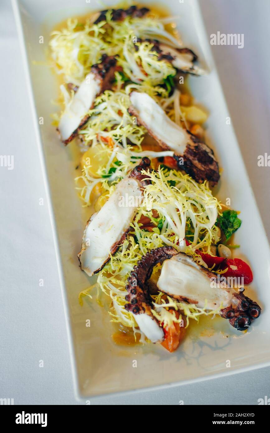 CHARRED octopus with vegetables and salad in restaurant Stock Photo - Alamy