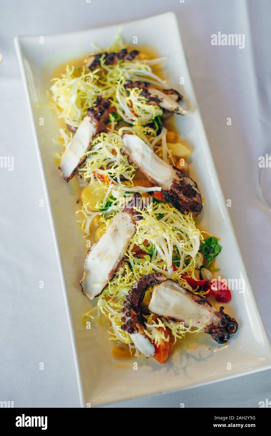 CHARRED octopus with vegetables and salad in restaurant Stock Photo - Alamy