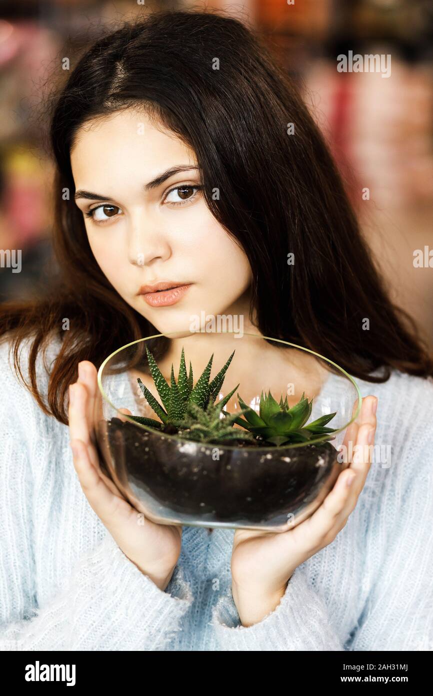 Pretty young brunette girl holding a beautiful terrarium with cactus in ...