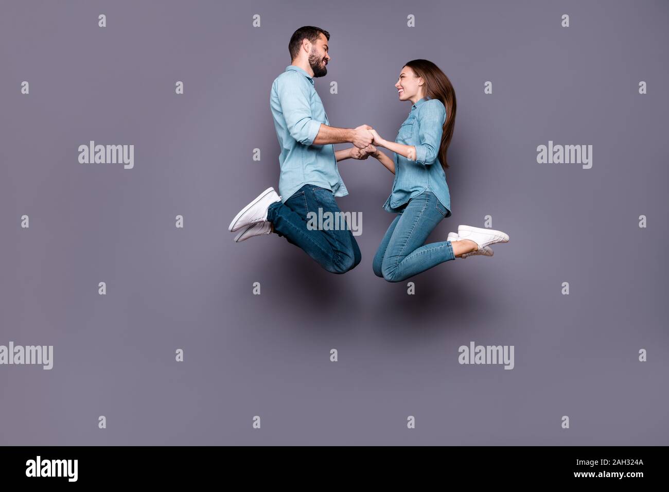 Full size photo of cheerful romantic students hold hand jump wear denim ...