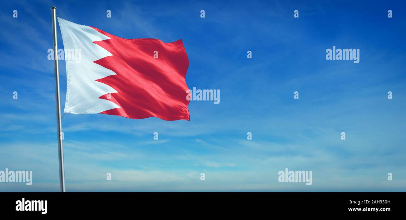 The National flag of Bahrain blowing in the wind in front of a clear ...