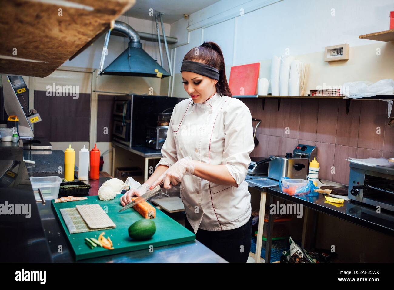 beautiful woman chef prepares fresh sushi in the kitchen of the ...