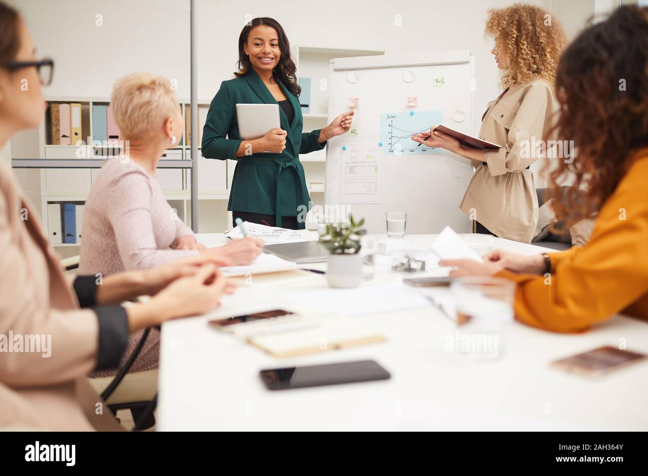 Two charming women making presentation together at businessmeeting in ...