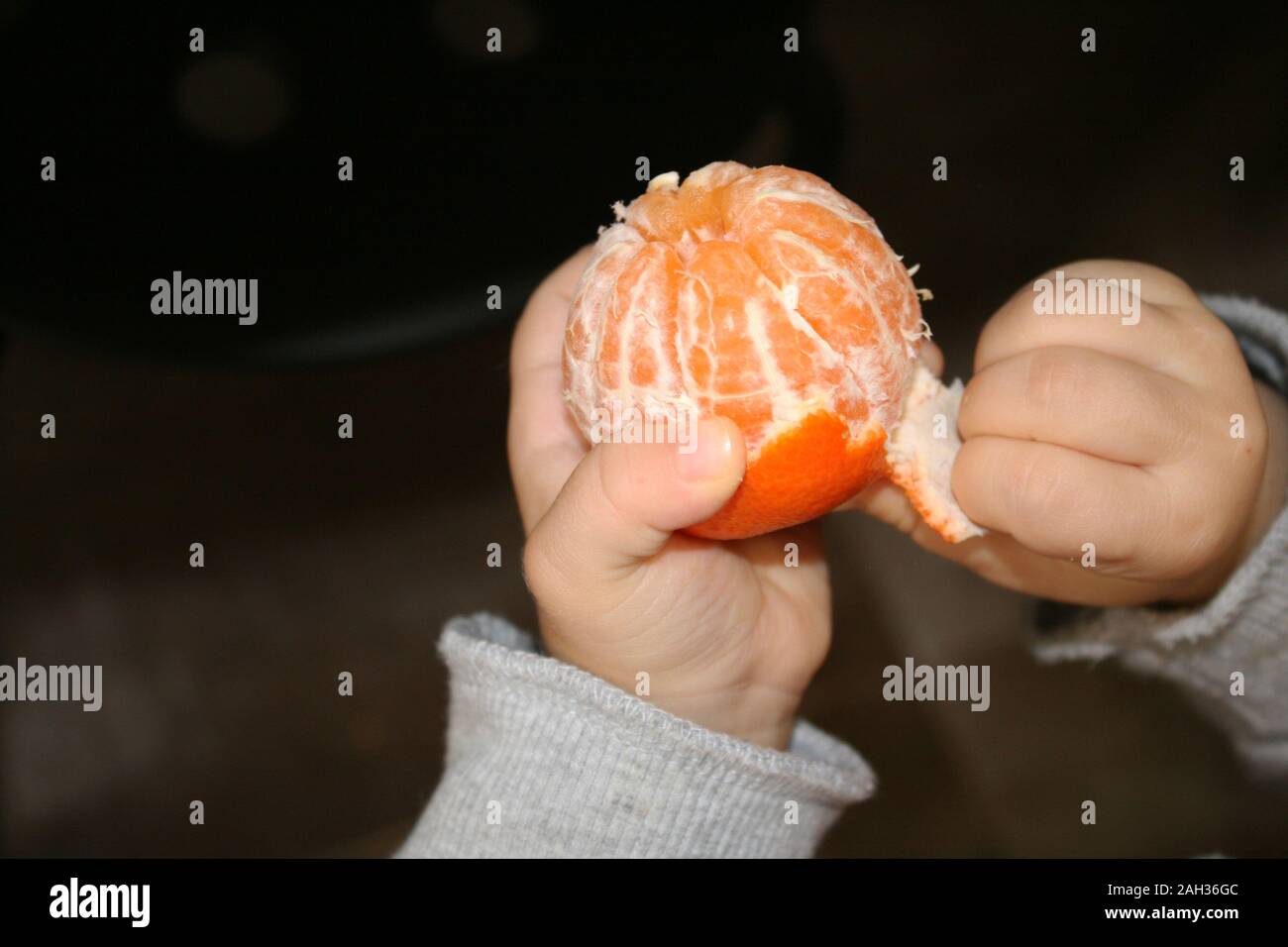 Little hands clean mandarin to have a snack Stock Photo - Alamy